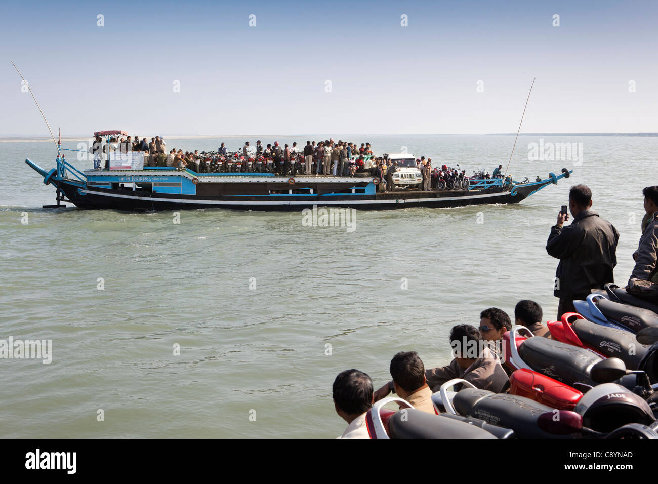 India, Assam, Jorhat, heavily overladen car and passenger ferry boat ...