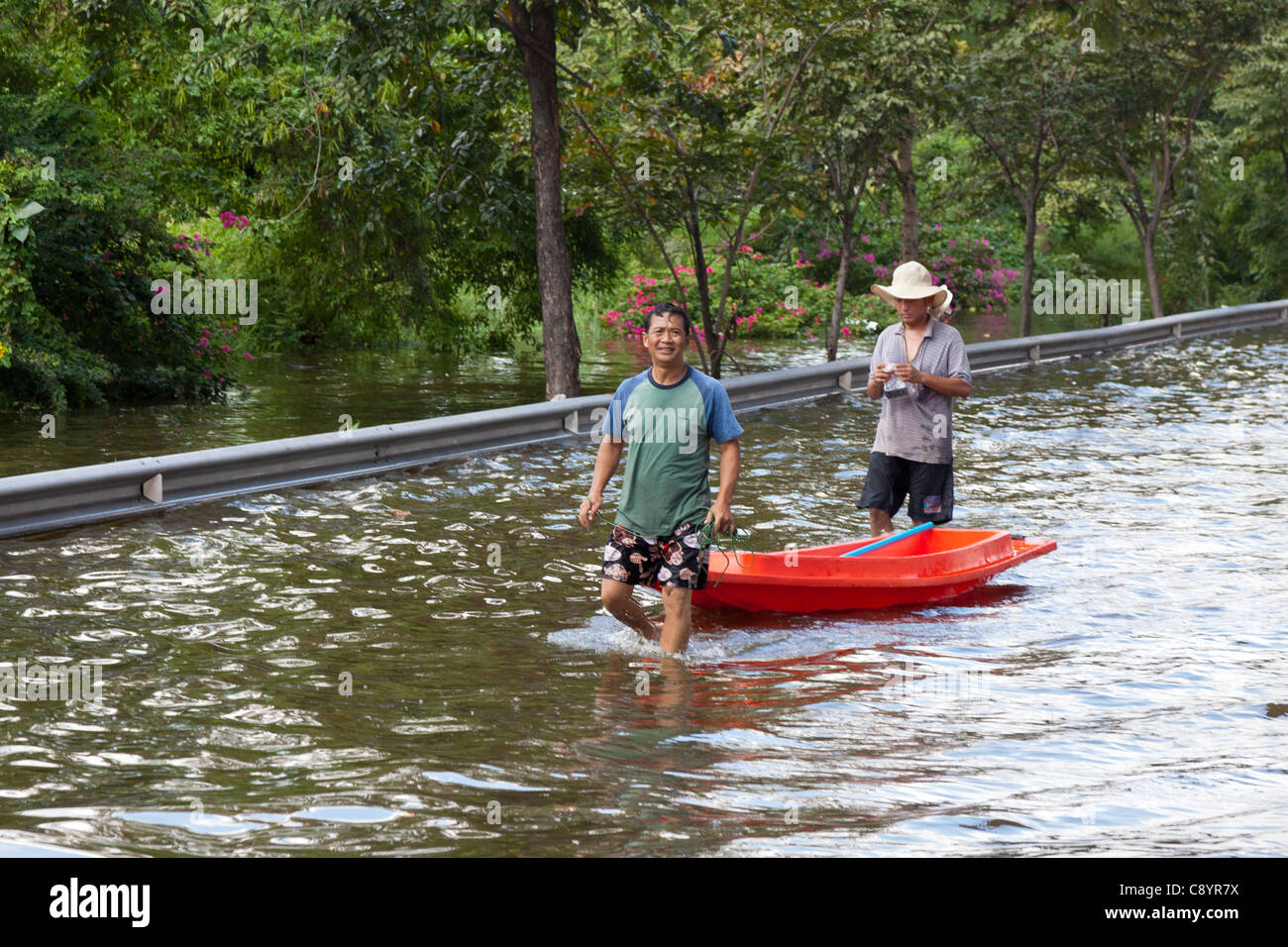 People wading through flood water with a boat in Bangkok city centre ...