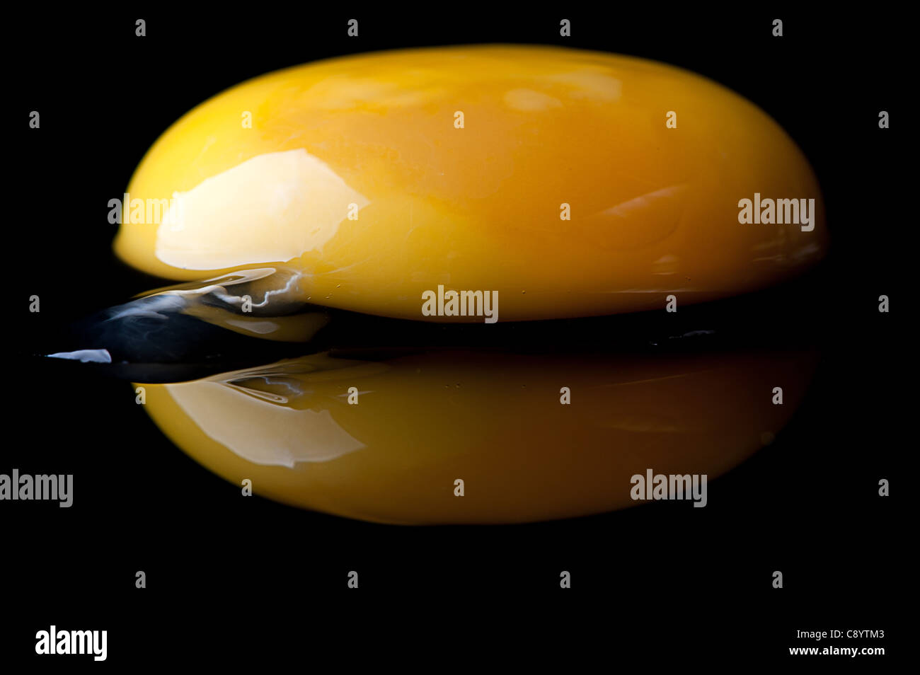 Raw egg and egg yolk and its reflection on a black reflecting surface ...