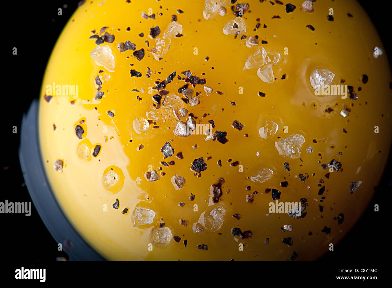 Aerial close up view of a Raw egg and egg yolk on a black reflecting ...