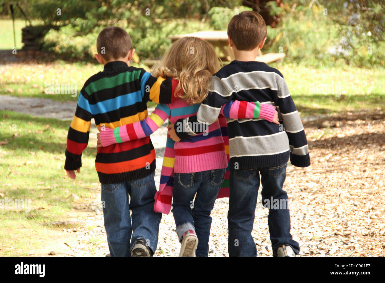 three kids walking through park arms around each other Stock Photo - Alamy