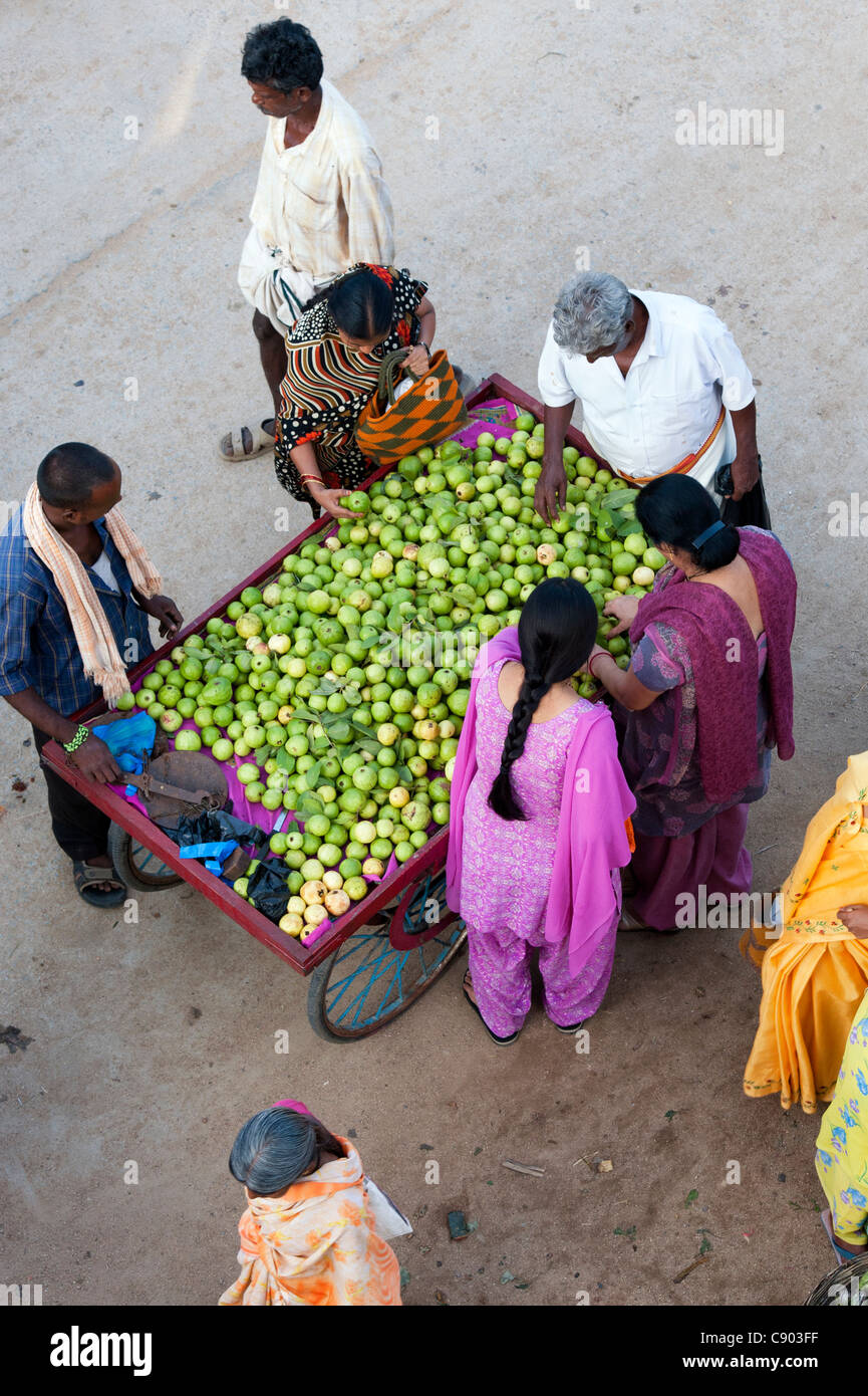Indian man selling Guava fruit from a cart at a street vegetable market ...