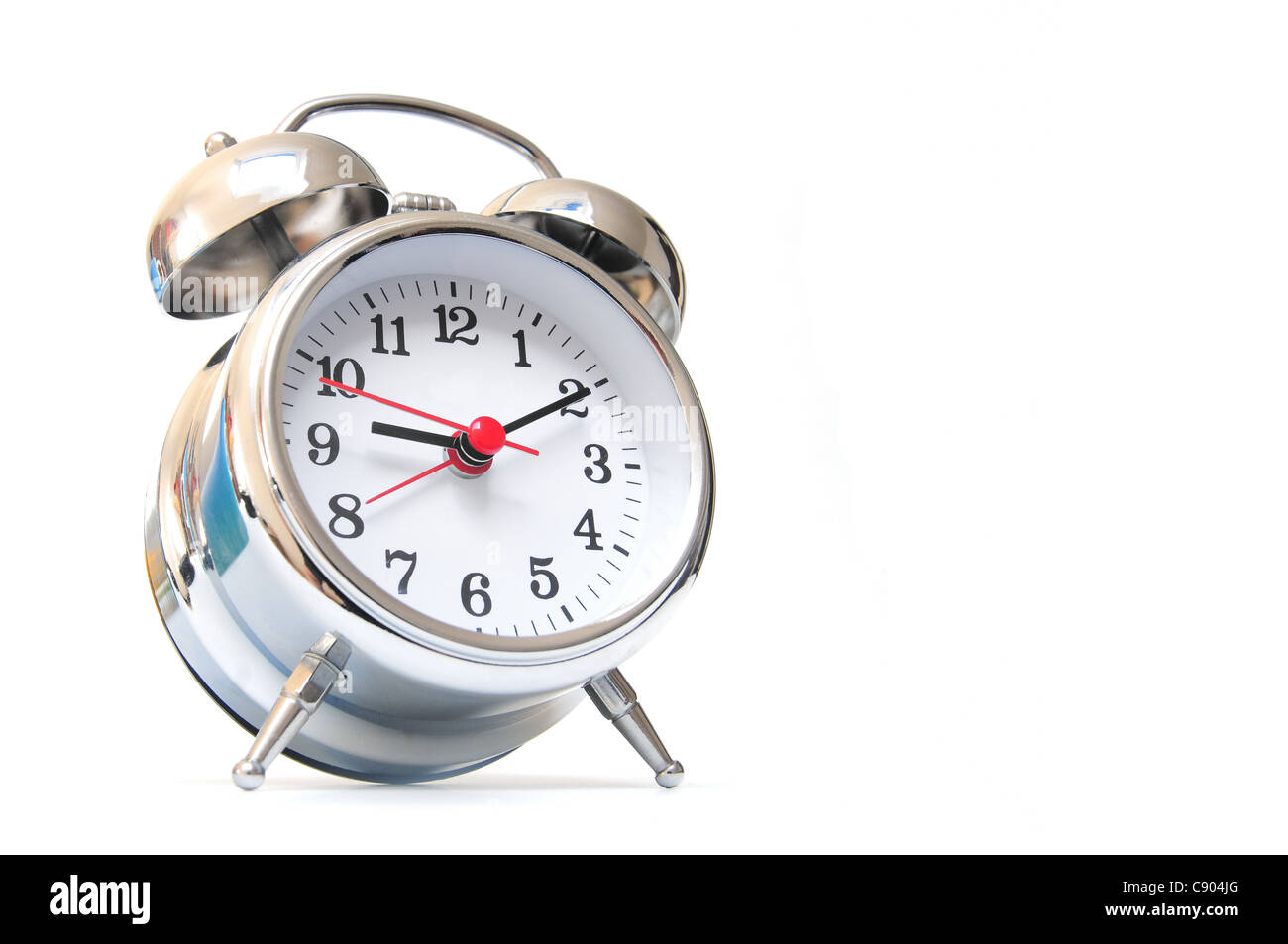 Silver colored alarm clock on white background Stock Photo - Alamy
