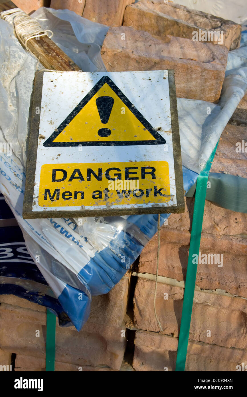 Danger men at work sign that has been left on top of a pile of new ...