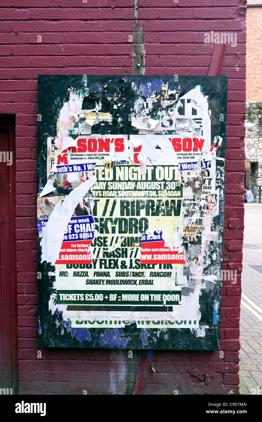 Old notice board covered in layers of torn and decaying paper posters ...