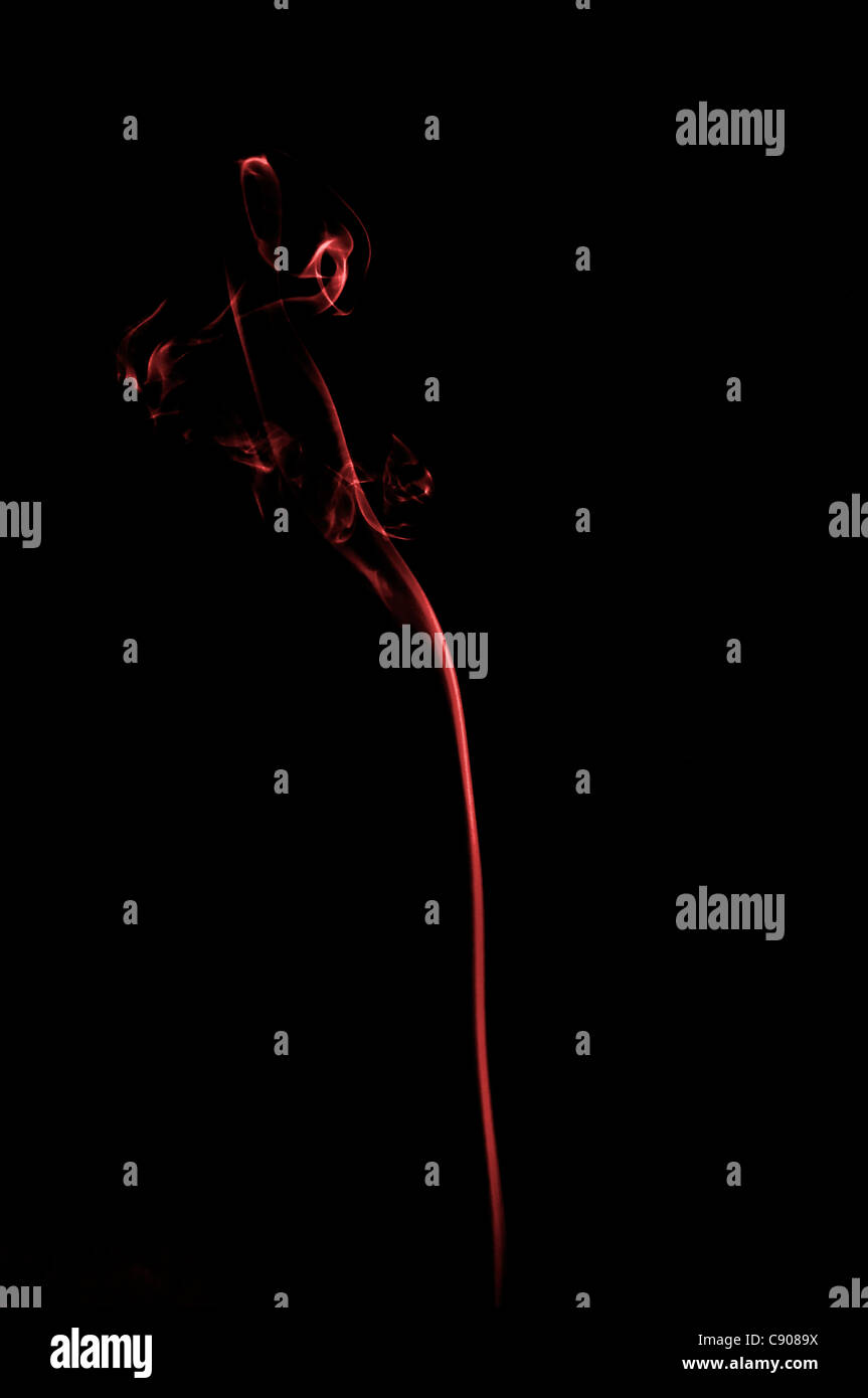 Wisps of red smoke against a black background Stock Photo - Alamy