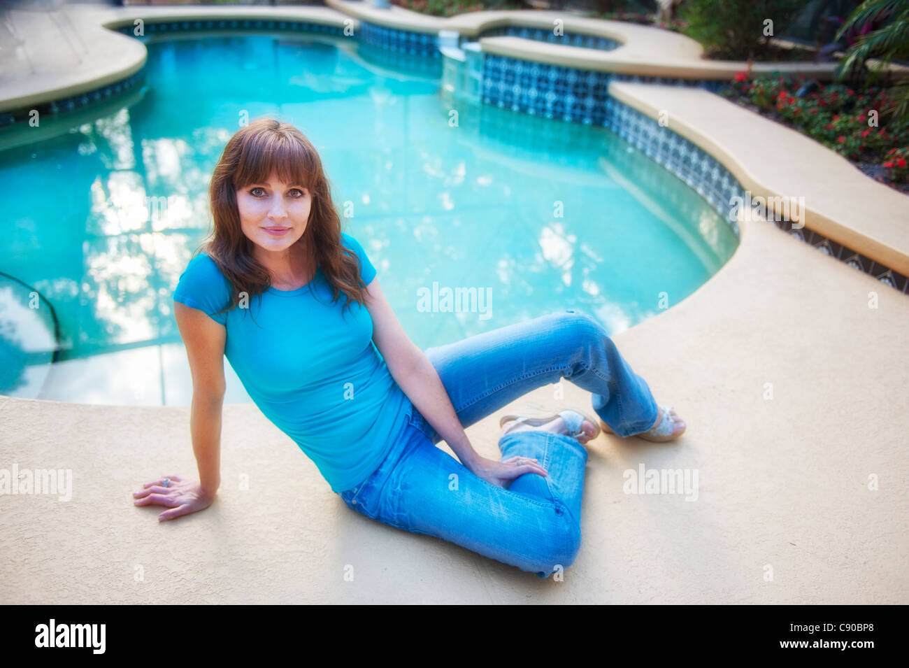 middle aged single woman sitting next to swimming pool wearing a short ...