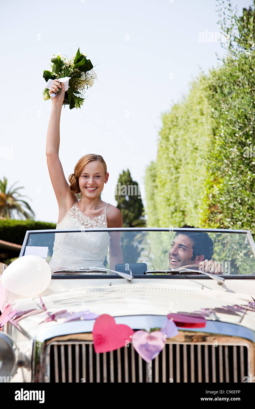 Newlyweds in classic car, bride holding bouquet Stock Photo - Alamy