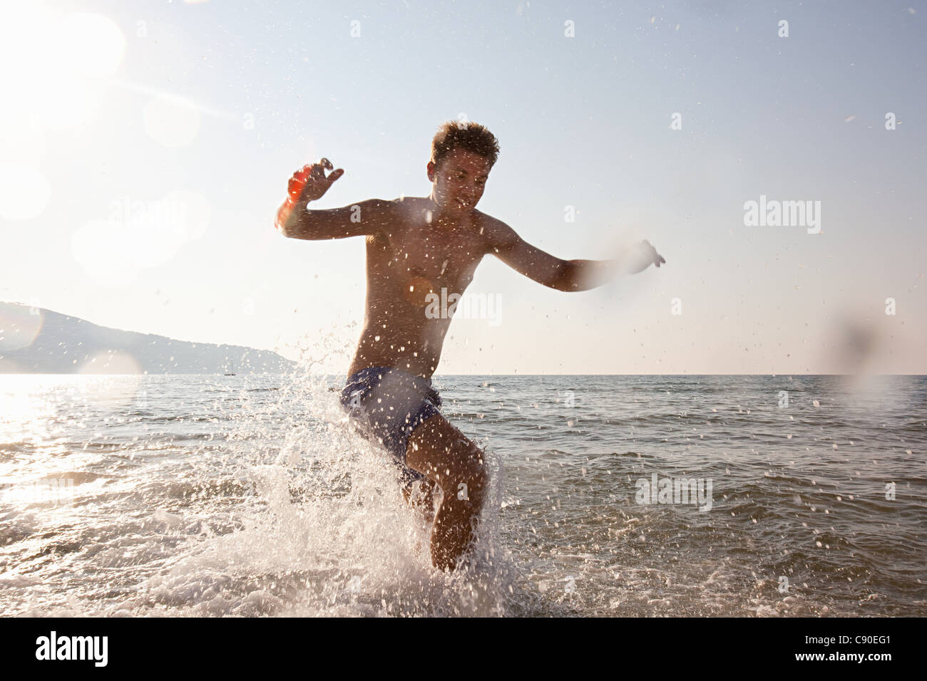 Young man splashing in sea Stock Photo - Alamy