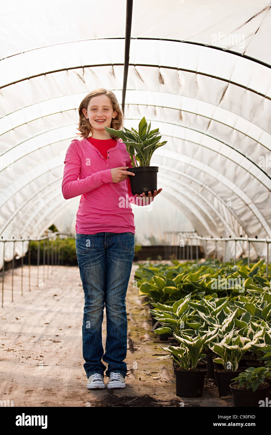 Girl holding pot plant in polytunnel, portrait Stock Photo - Alamy