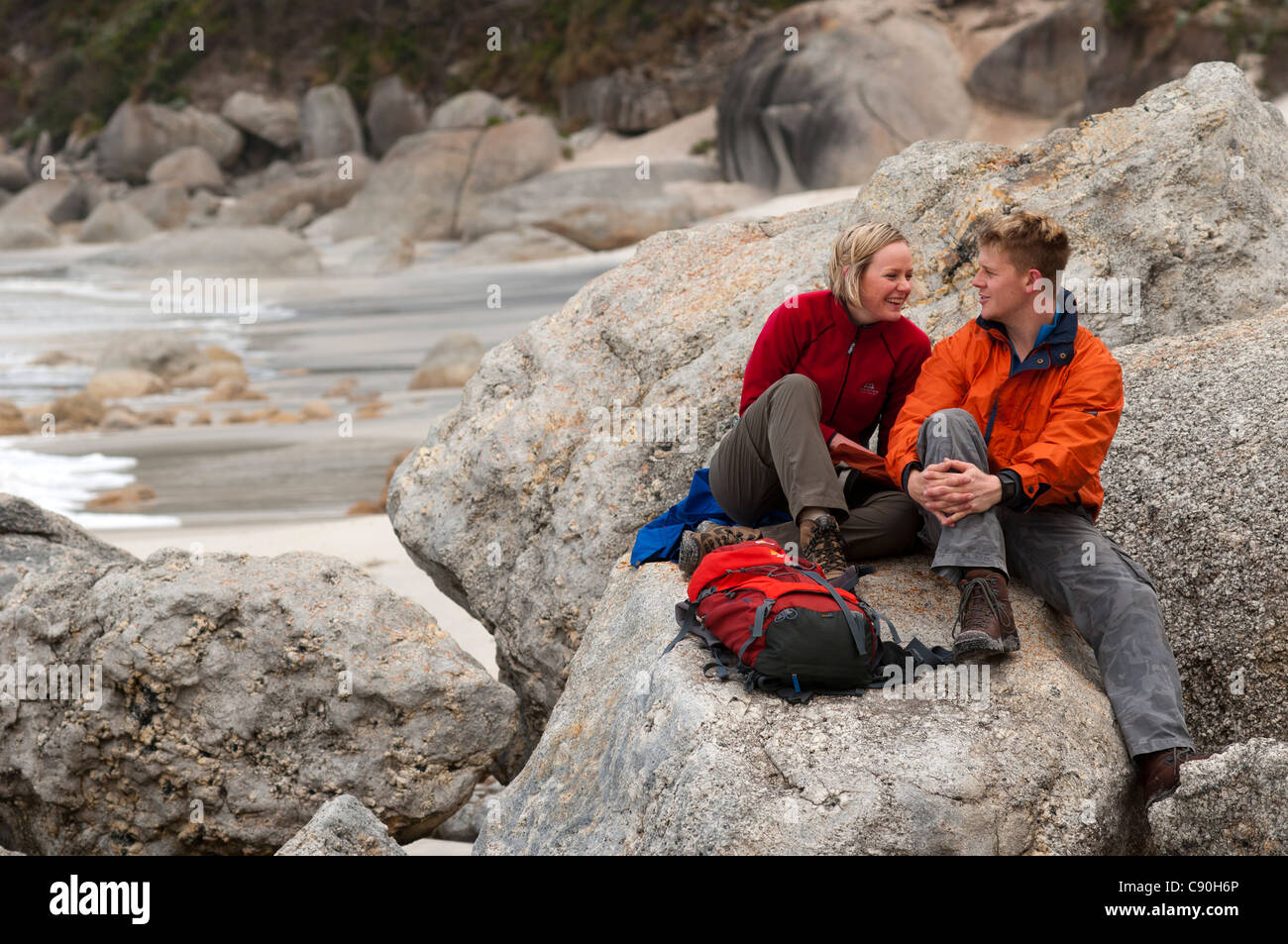 Couple having a rest on rocks at Little Oberon Bay, Wilsons Promontory ...
