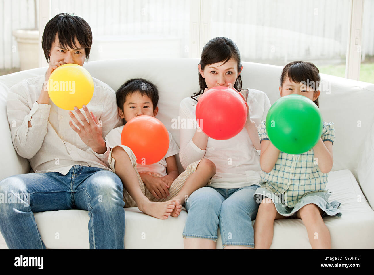 Family with two children blowing up balloons Stock Photo - Alamy