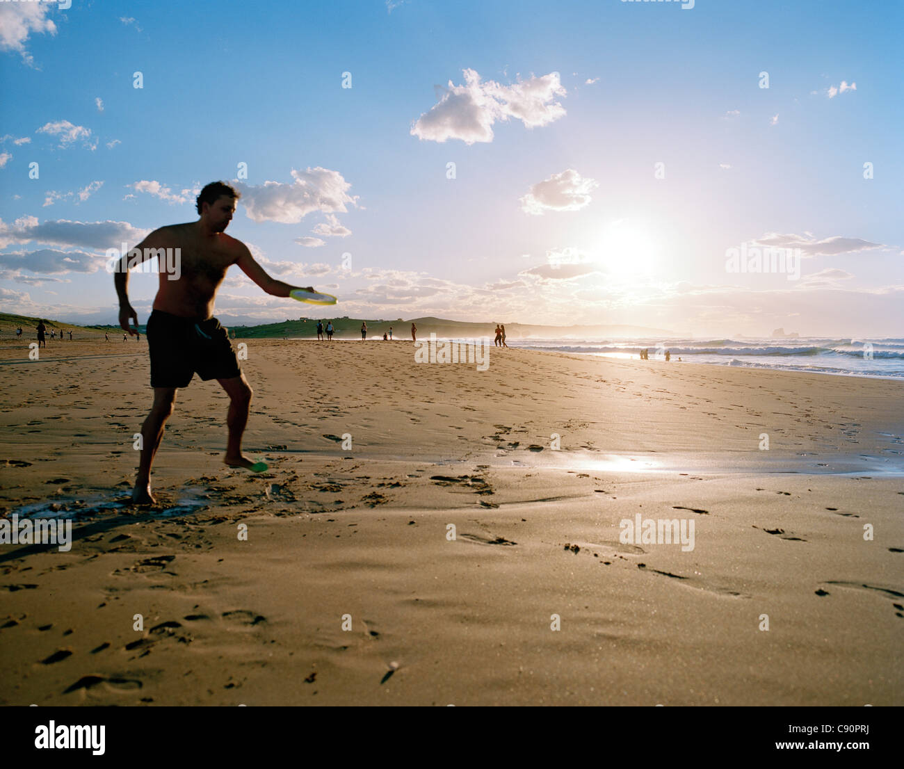 Man throwing frisbee at sunset on the beach, Playa de Valdearenas, west ...