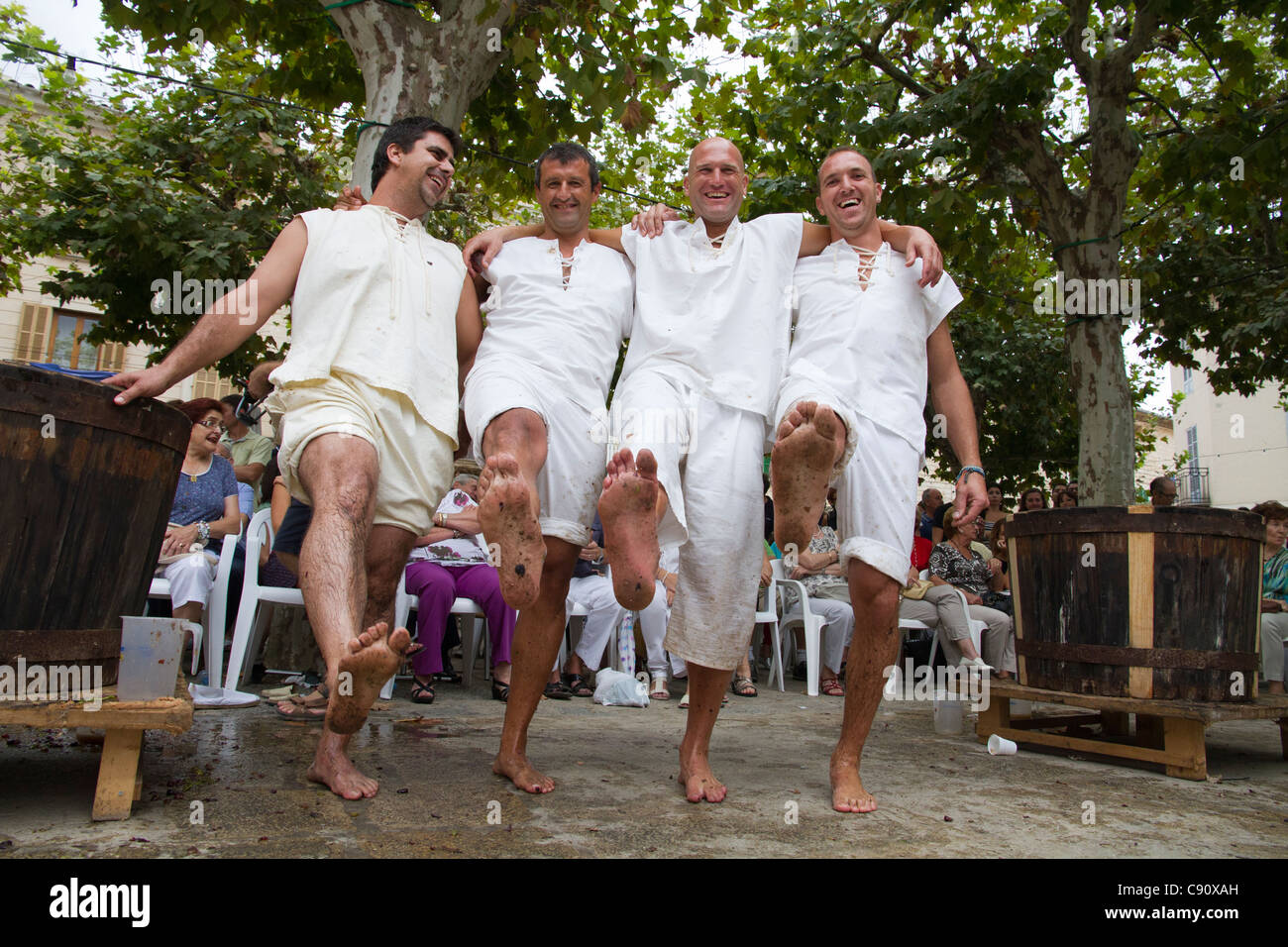 Group of men showing feet after pressing grapes at grape harvest ...