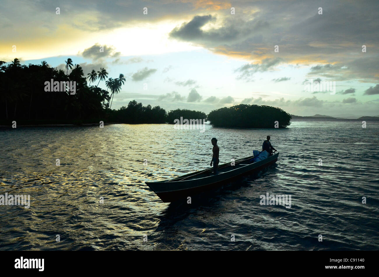 Papuan men in fishing boat at sunset, Raja Ampat islands near West ...