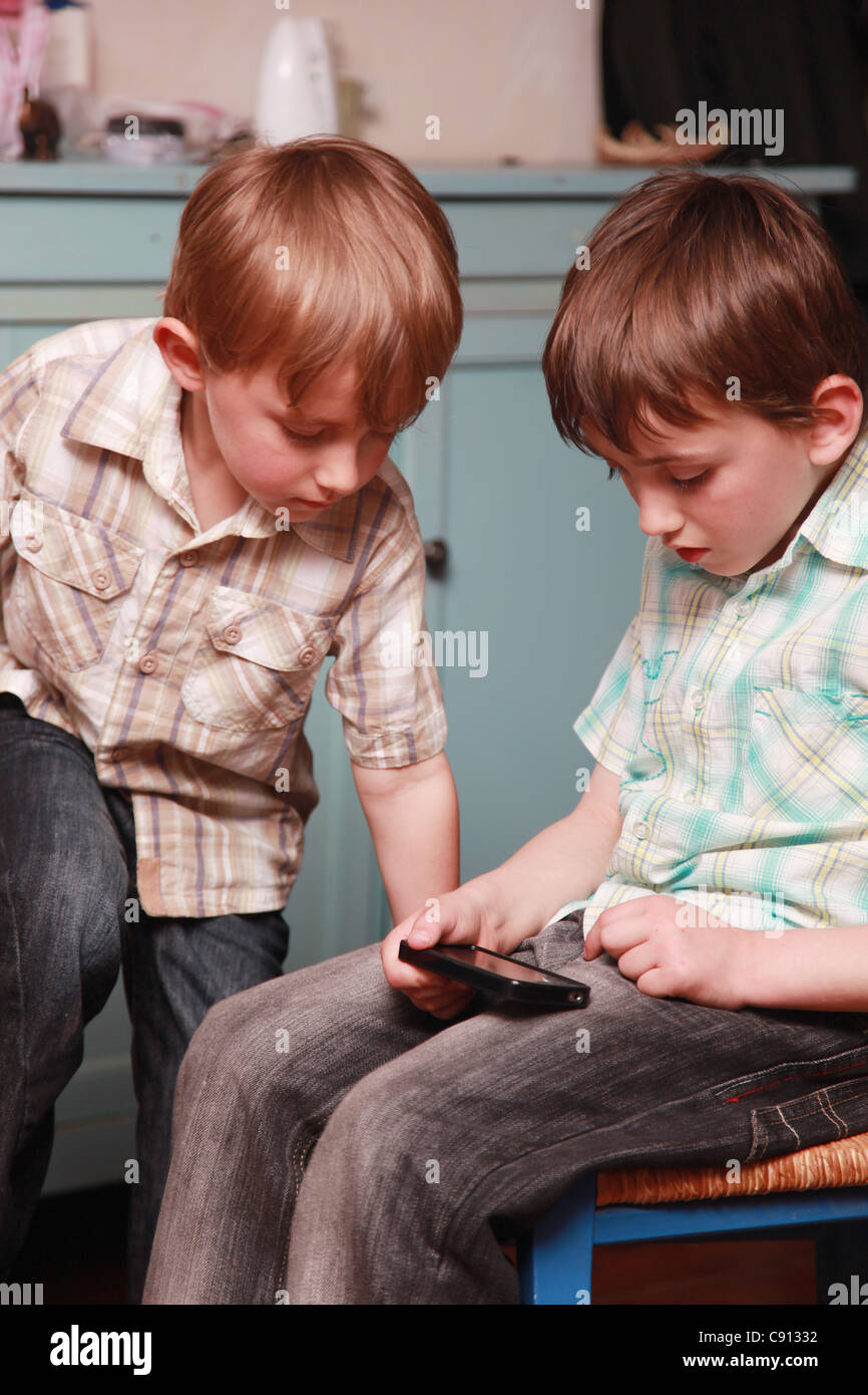 2 young brothers playing a hand held game Stock Photo - Alamy