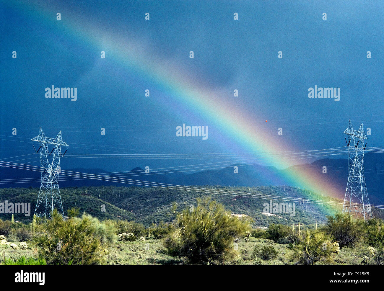 Electrical transmission lines and towers with a vivid, dramatic rainbow ...