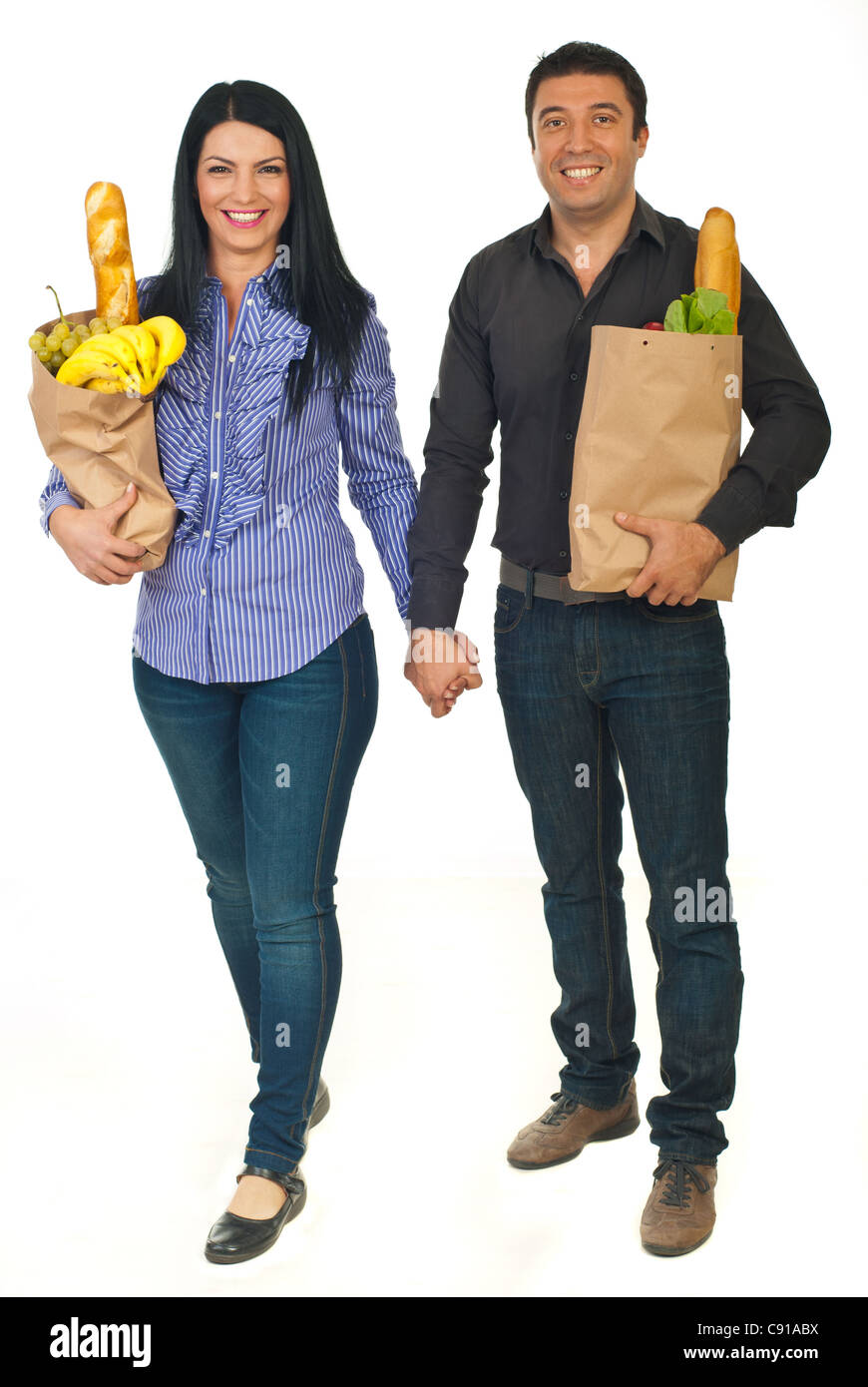 Full length of cheerful couple holding hands and carrying bags with ...
