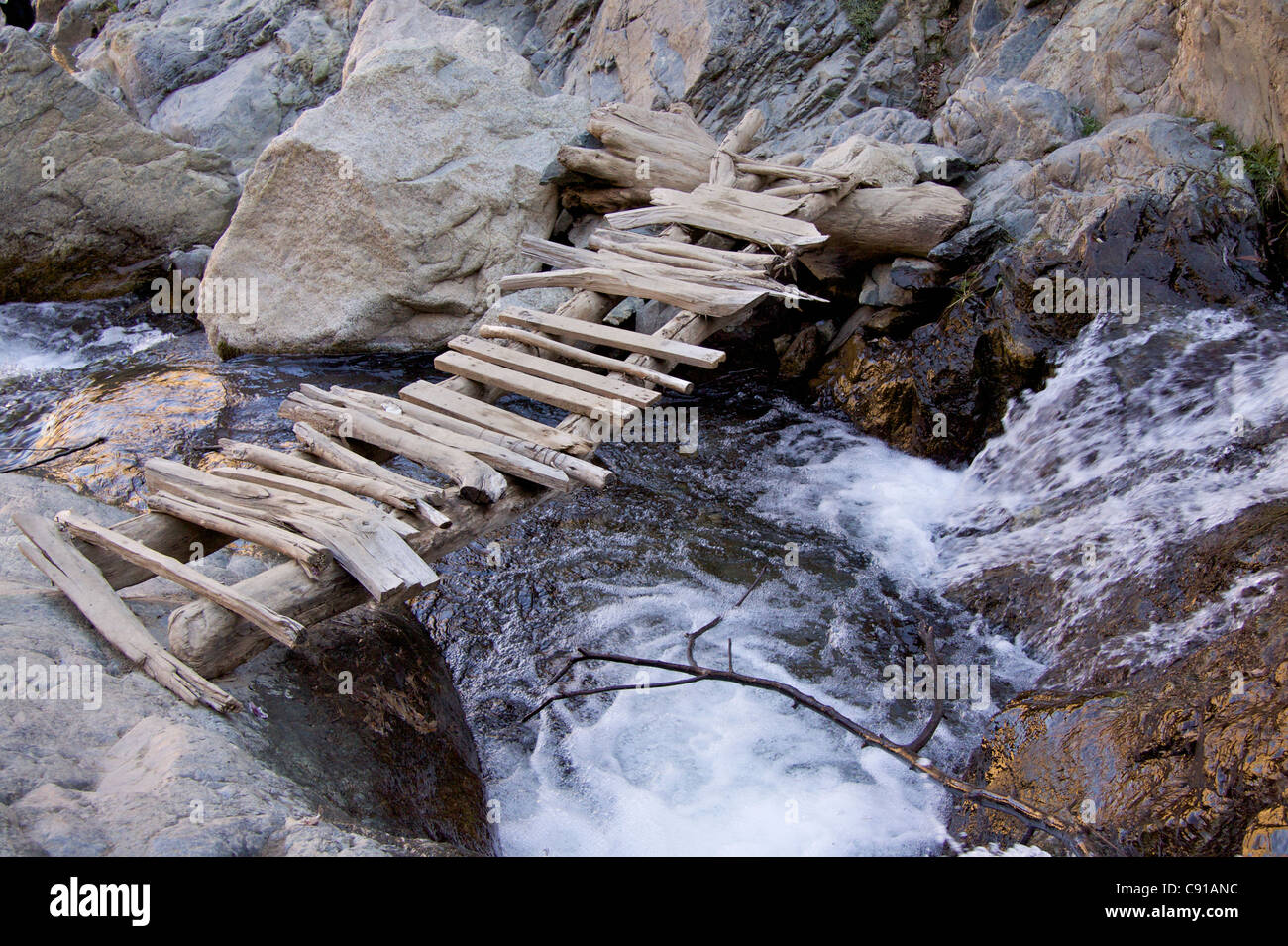 There is a handmade wooden footbridge over a gorge tributary of the ...