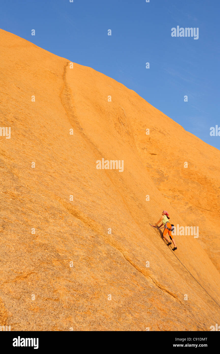 Woman climbing at red rock face, Great Spitzkoppe, Namibia Stock Photo ...