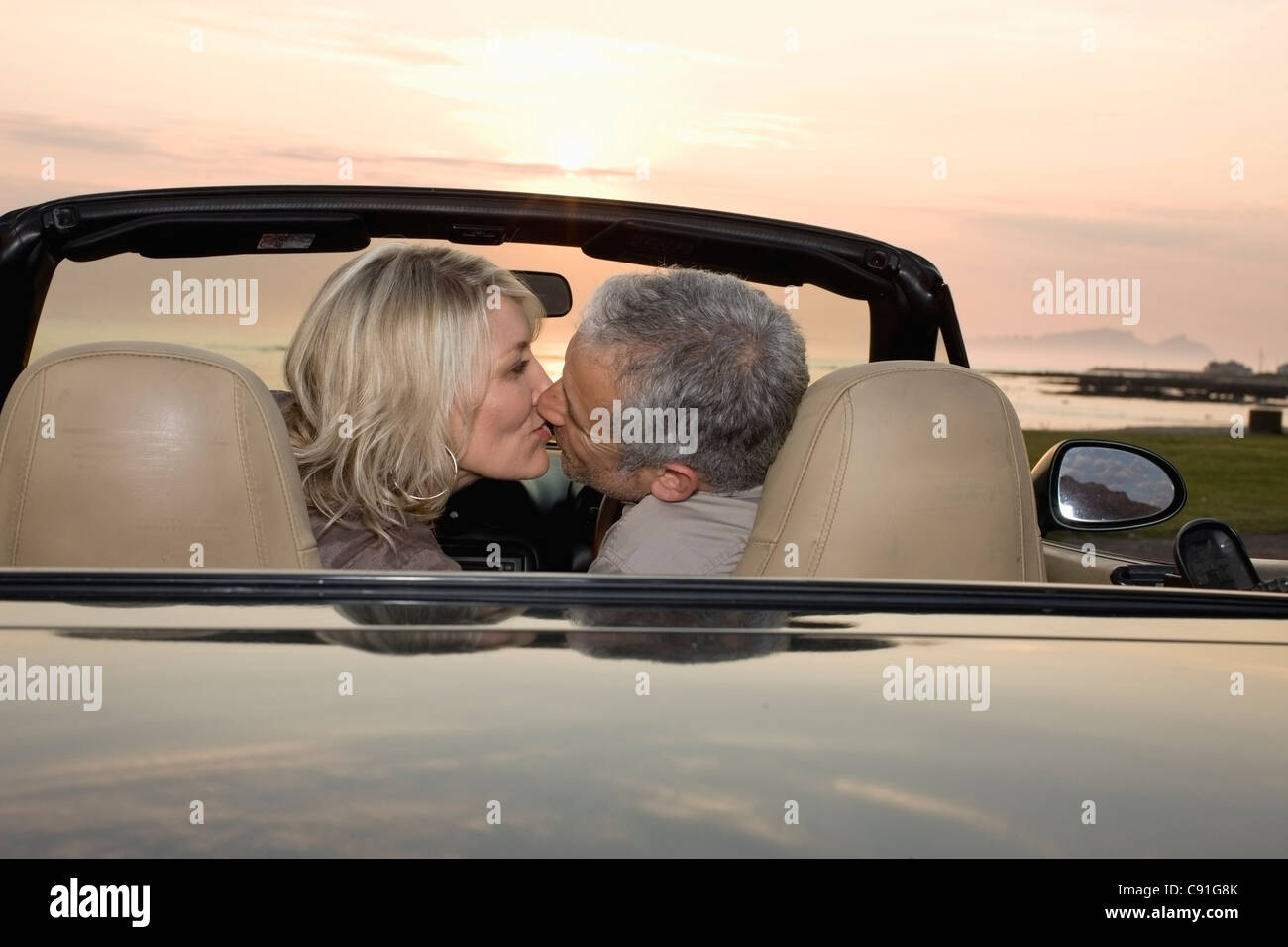 Couple kissing in convertible at sunset Stock Photo - Alamy