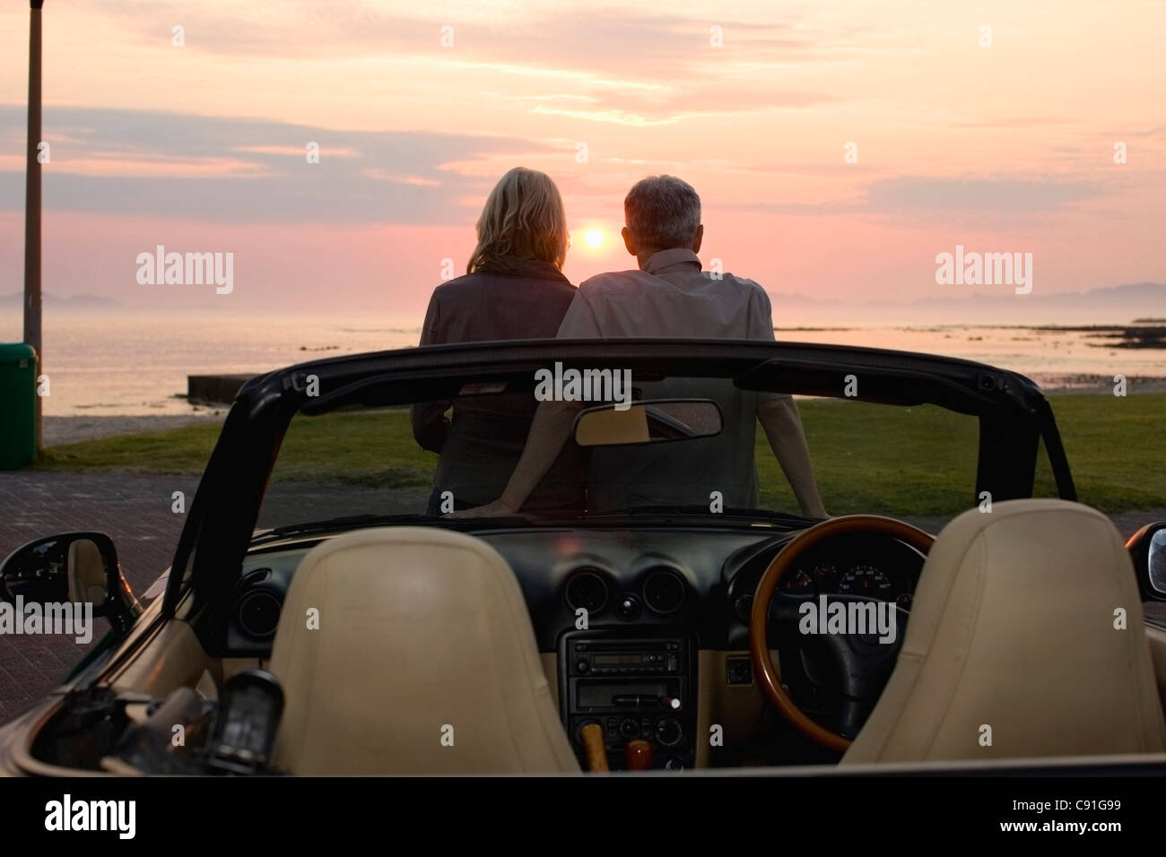 Couple admiring sunset in convertible Stock Photo - Alamy