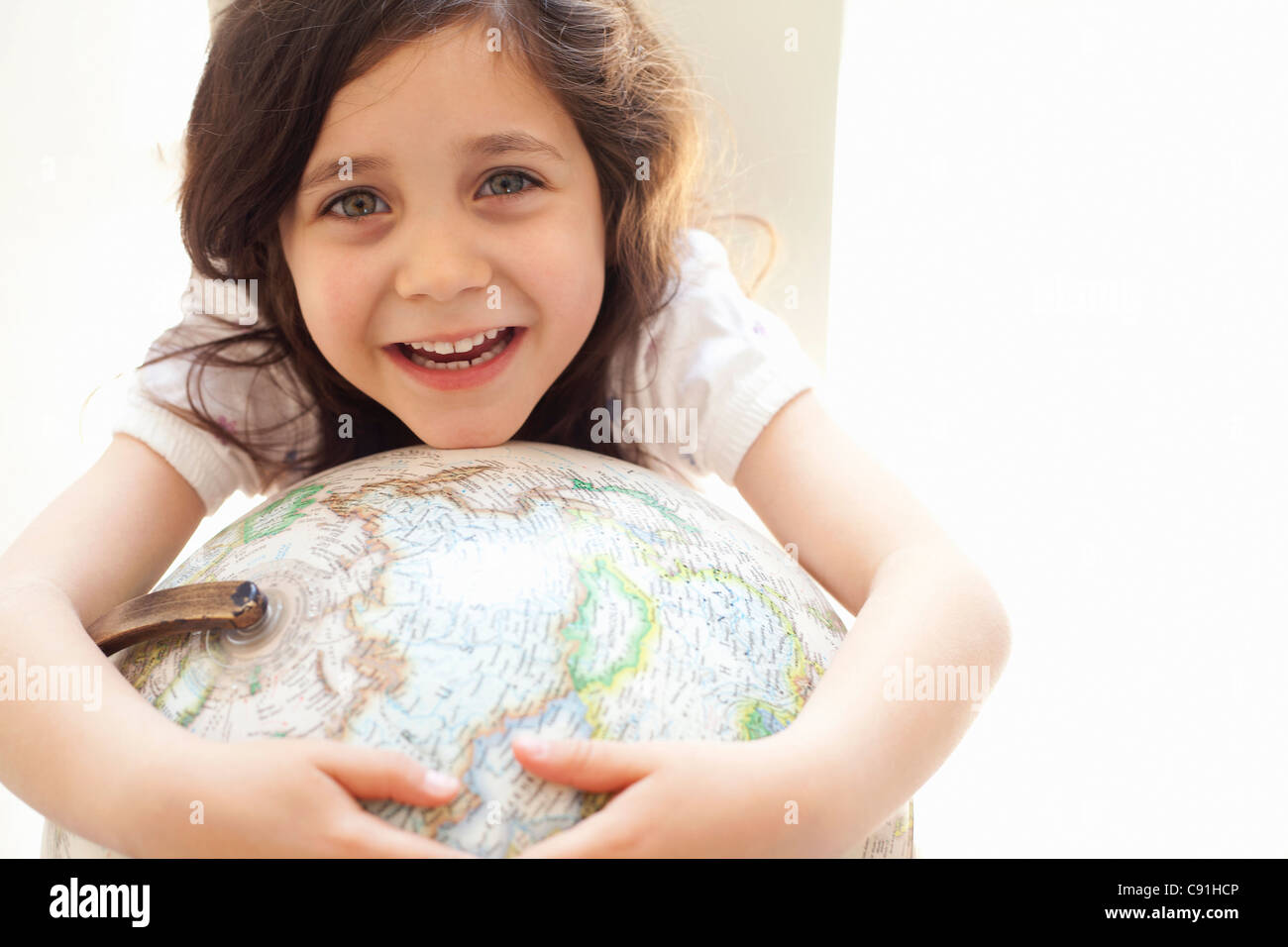 Smiling girl hugging globe indoors Stock Photo - Alamy