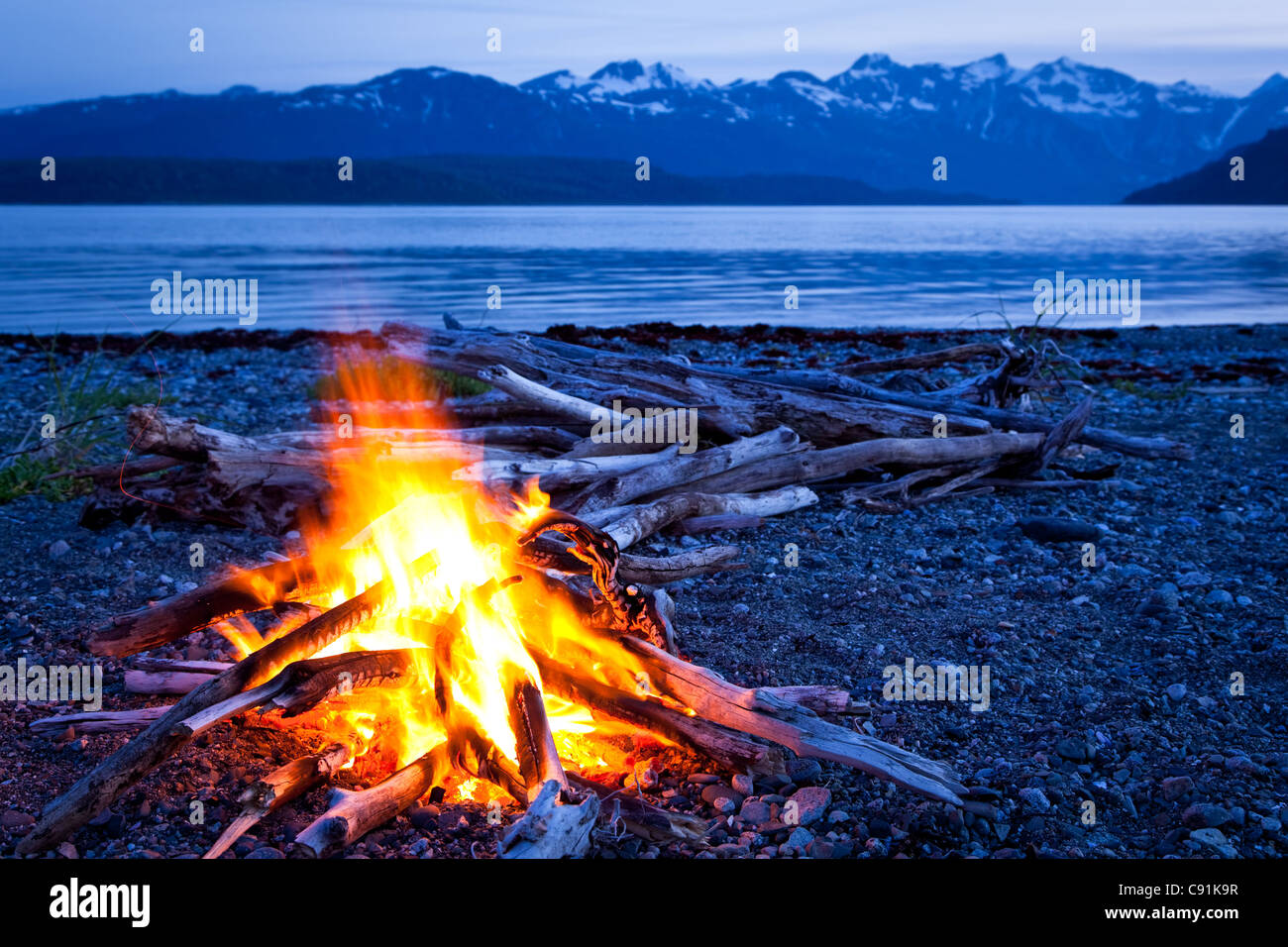 Campfire at dusk on a remote coastal beach in Goose Cove, Muir Inlet ...