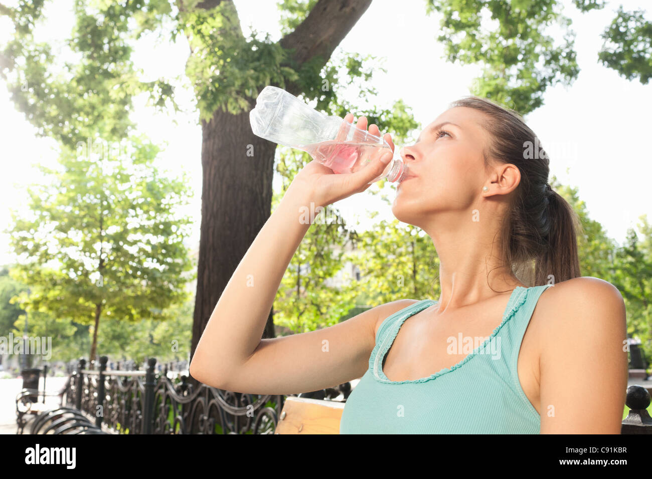 Woman drinking water on park bench Stock Photo - Alamy