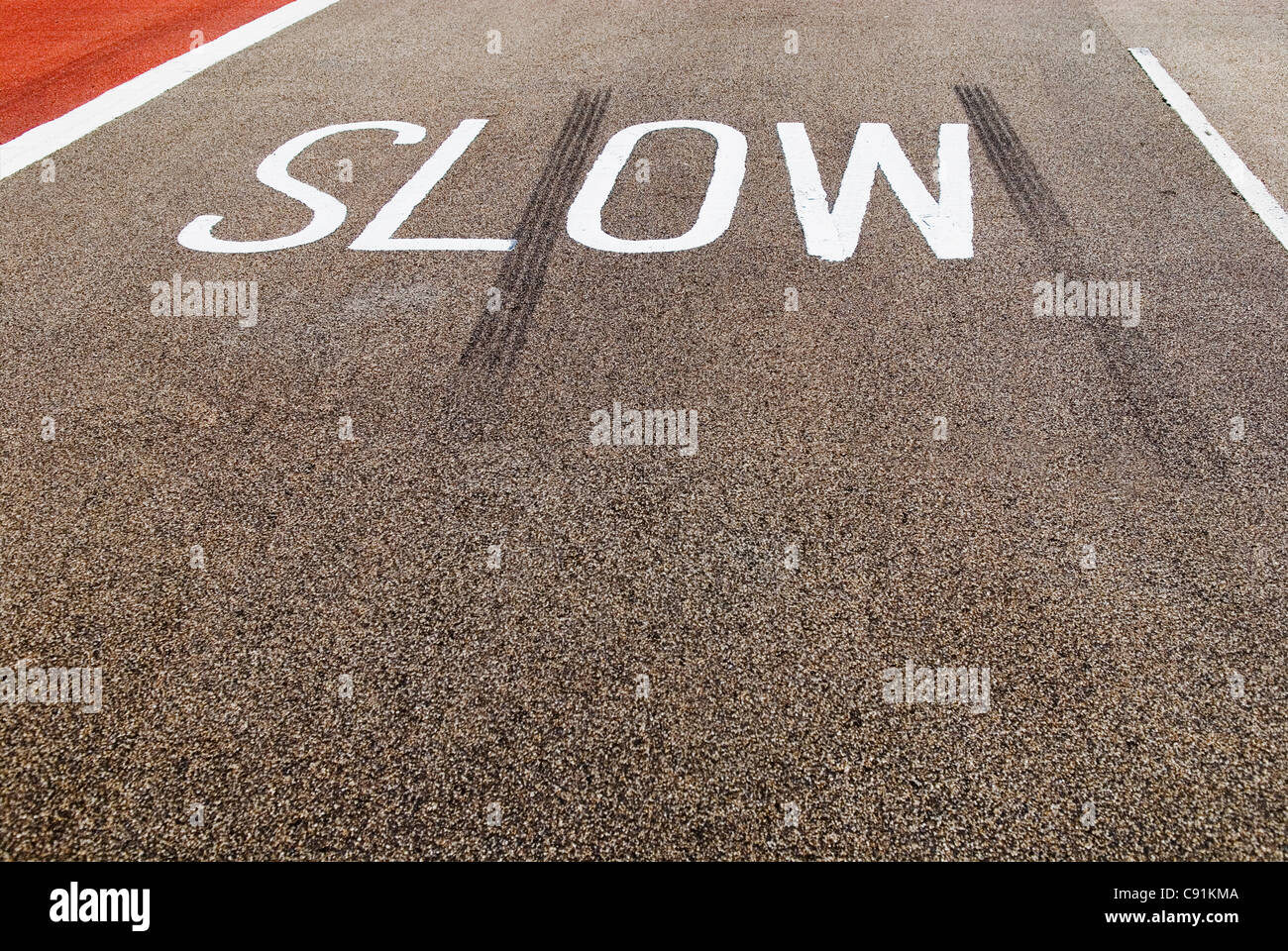 a warning sign saying SLOW painted on the road with skid marks next to ...