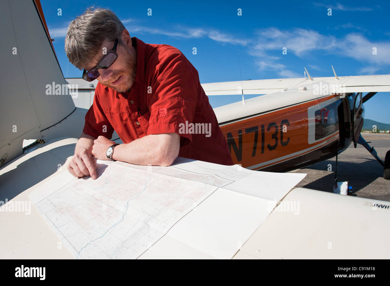 Helio Courier pilot consults a map before getting ready to fly to the ...