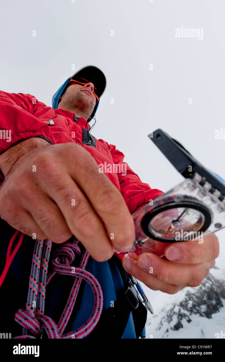 Mountaineer taking a compass bearing in the Tordrillo Mountains, Winter ...