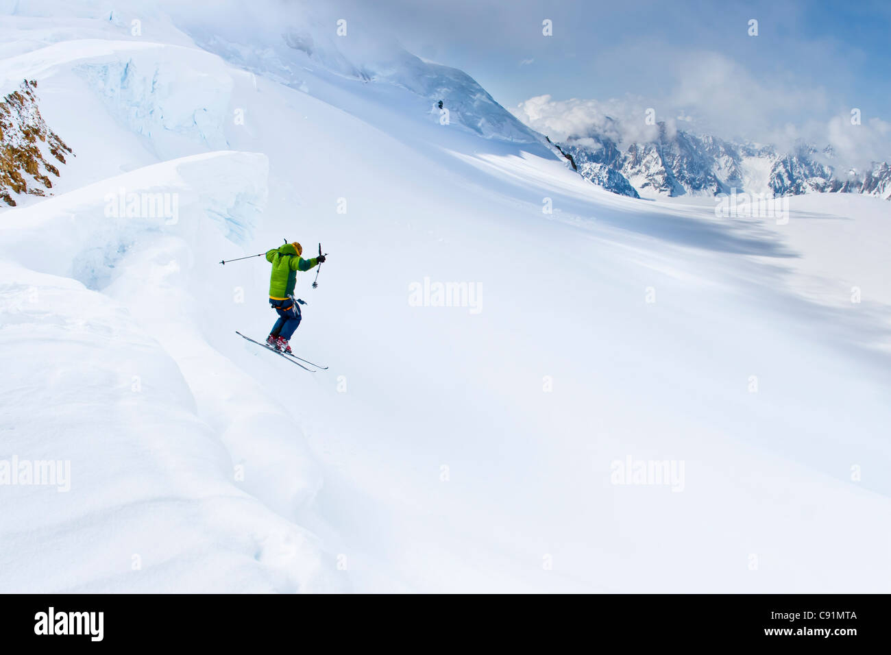 Skier jumping a bergschrund crevasse onto powder on Hayes Glacier ...