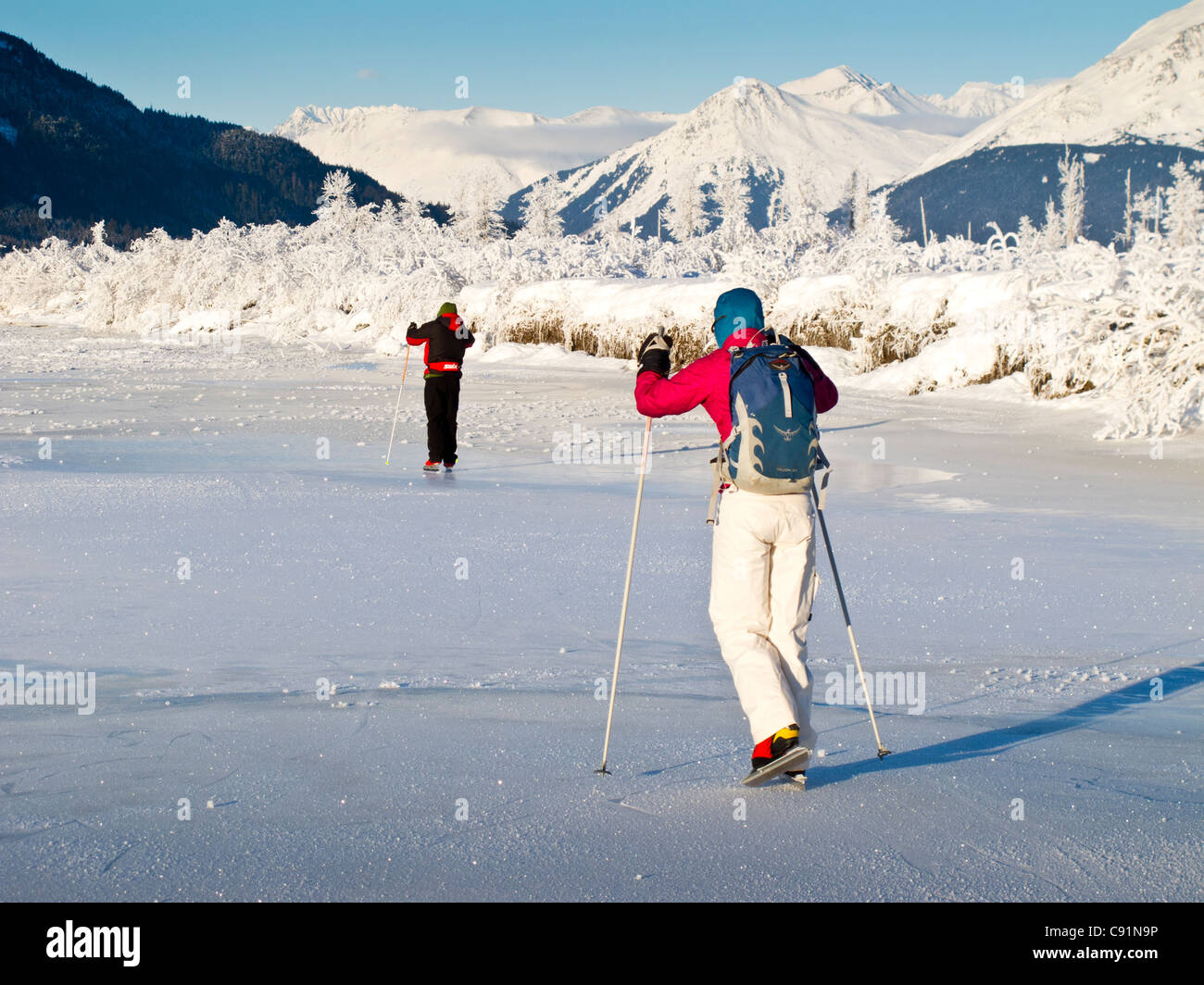 Couple Nordic ice skating on the frozen Placer River, Kenai Mountains ...