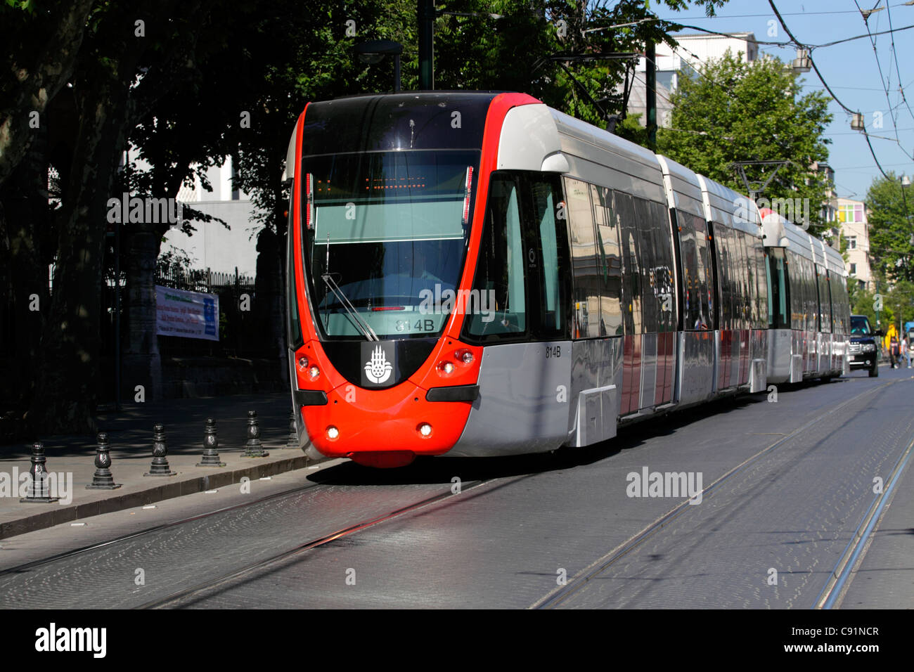 Red Alstom Citadis tram in a narrow street in the European part of ...
