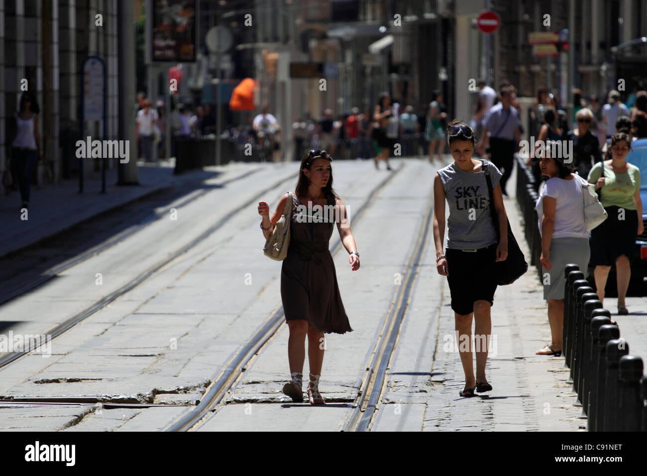 Street scene in central Sofia, Bulgaria; crowd on the side walk, two girls walking on tram ...