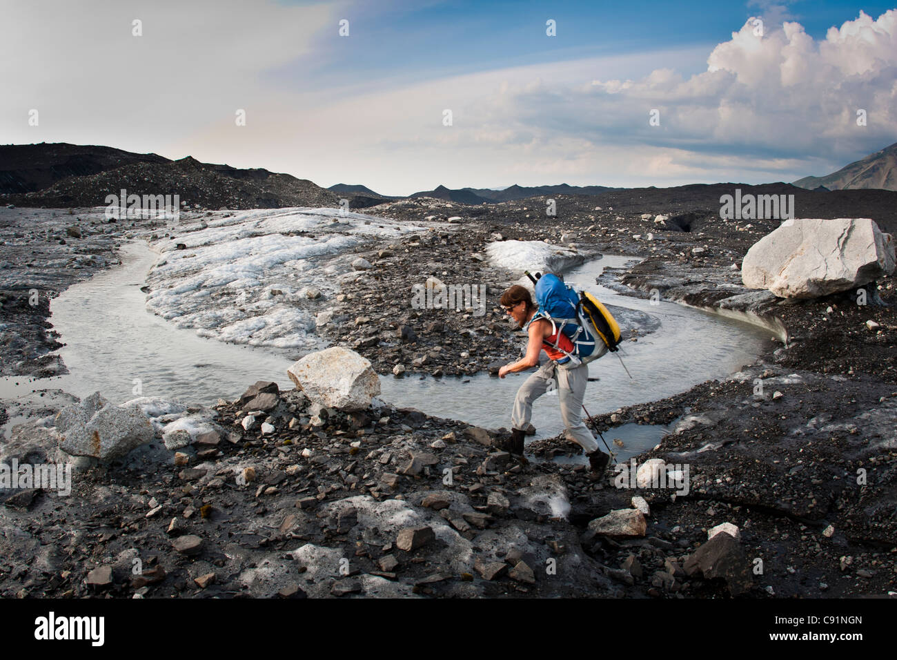 Woman hiking across an ice and rock moraine on the Muldrow Glacier near ...