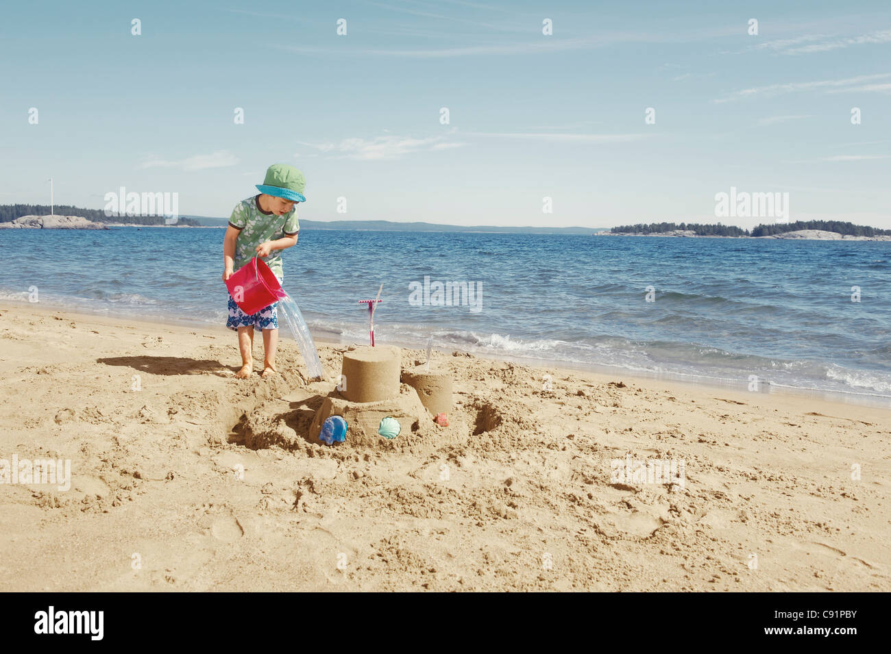 Child making moat around sandcastle Stock Photo - Alamy
