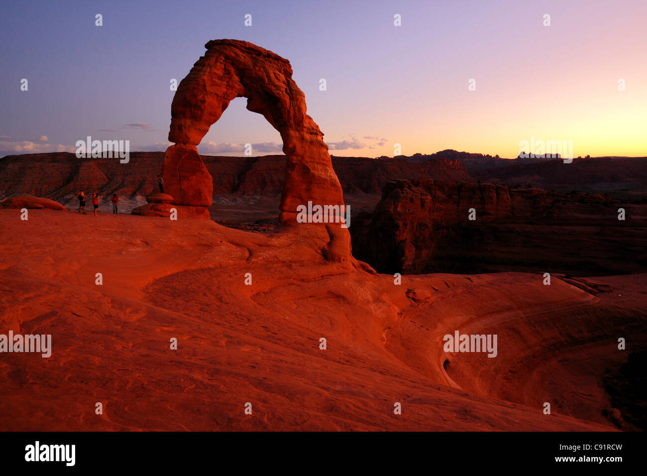 Tourists below Delicate Arch at dusk, Arches National Park Stock Photo ...
