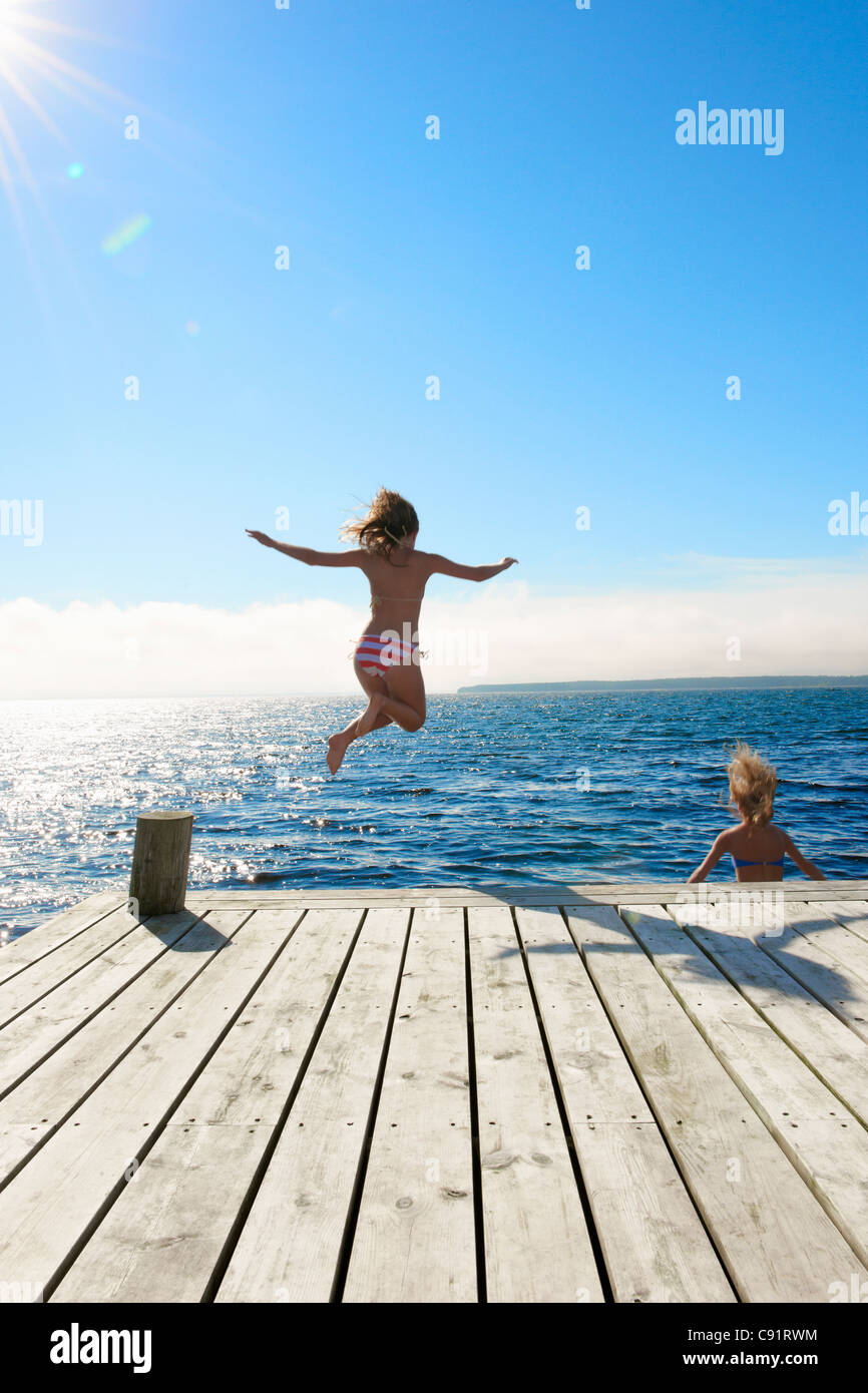 Teenage girls jumping into lake Stock Photo - Alamy