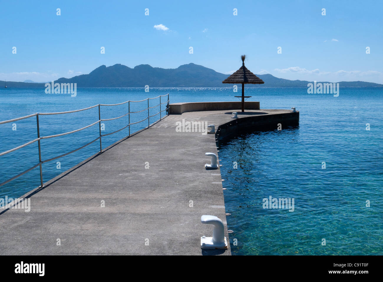 Small pier leading out to sea with seat and parasol, Formentor ...