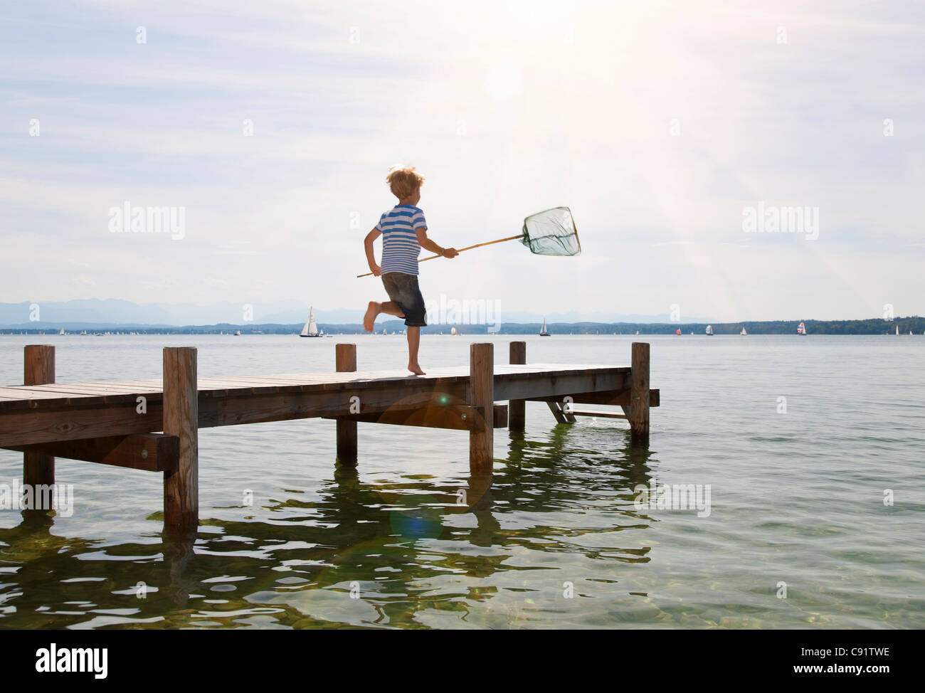 Boy running on dock with fishing net Stock Photo - Alamy