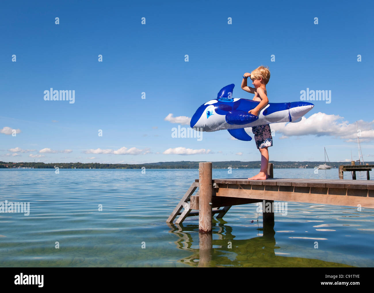 Boy holding inflatable whale on dock Stock Photo - Alamy