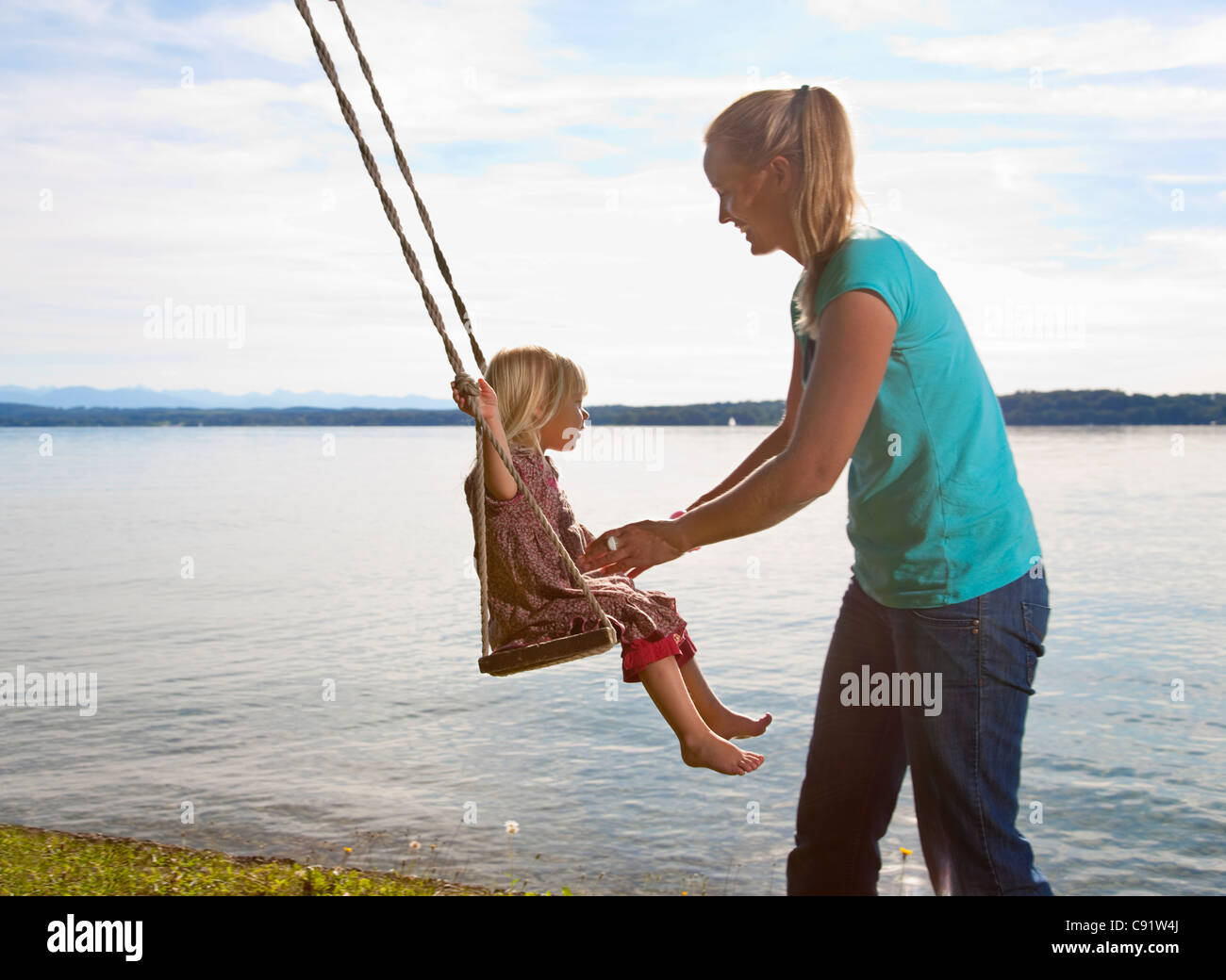 Mother pushing daughter on swing Stock Photo - Alamy