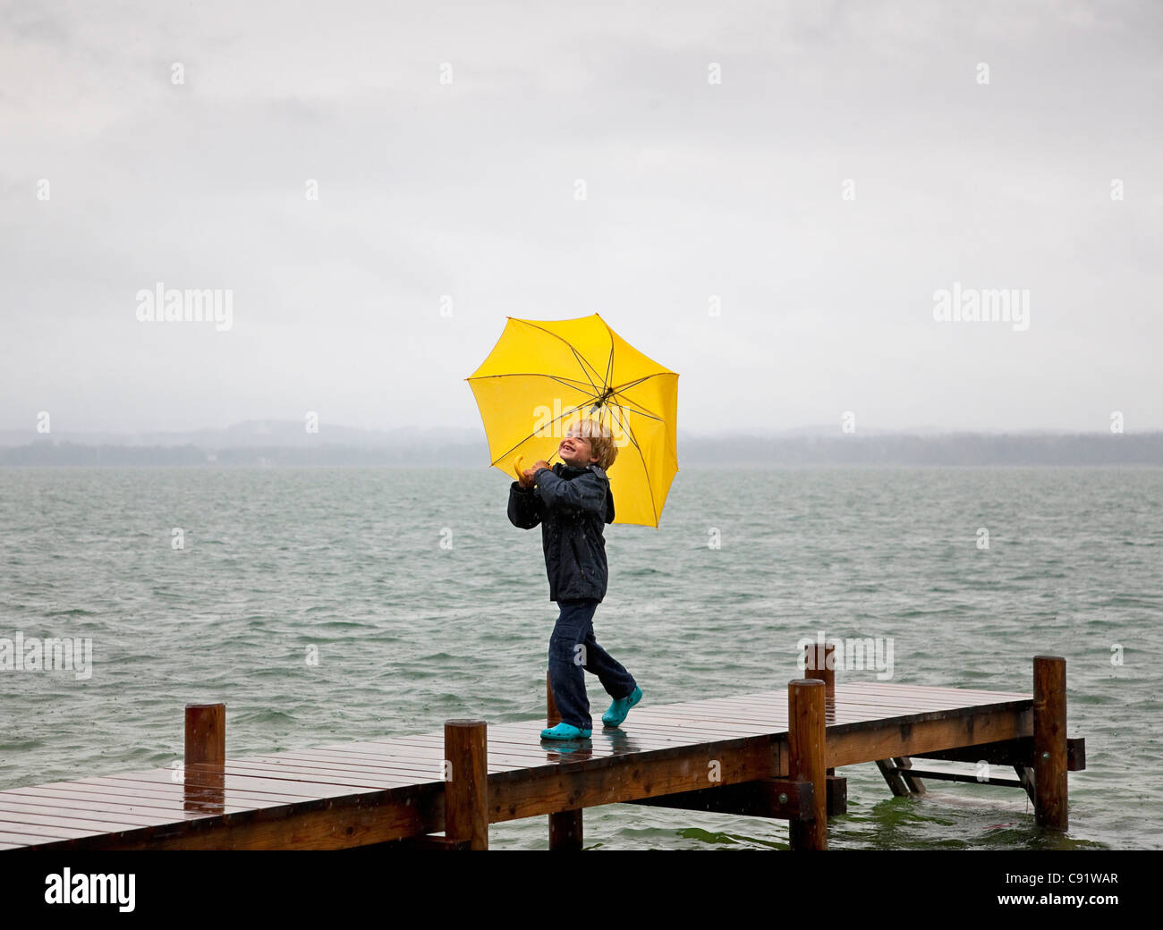 Boy carrying umbrella on wooden dock Stock Photo - Alamy