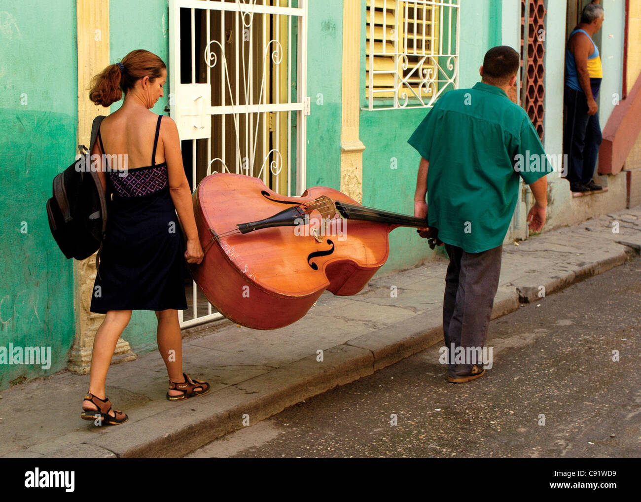 Carrying a musical instrument through the city streets. Centro Habana ...