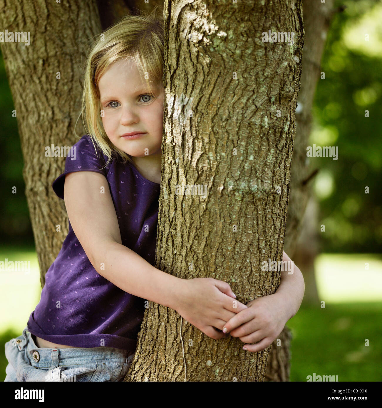 Smiling girl hugging tree Stock Photo - Alamy