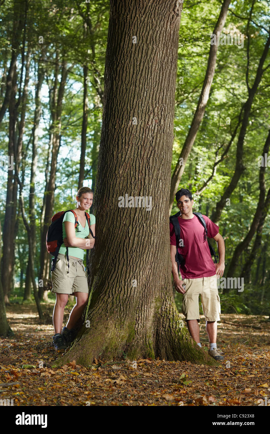 young man and woman during hiking excursion, posing near large tree and ...