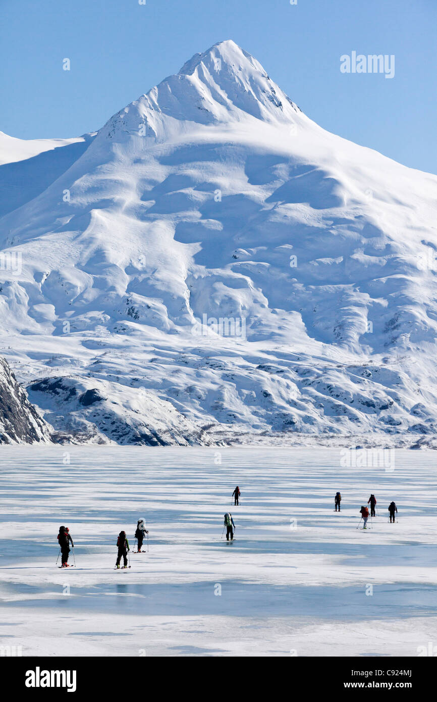 A group of skiers ski across frozen Portage Lake with Mount Bard in the ...