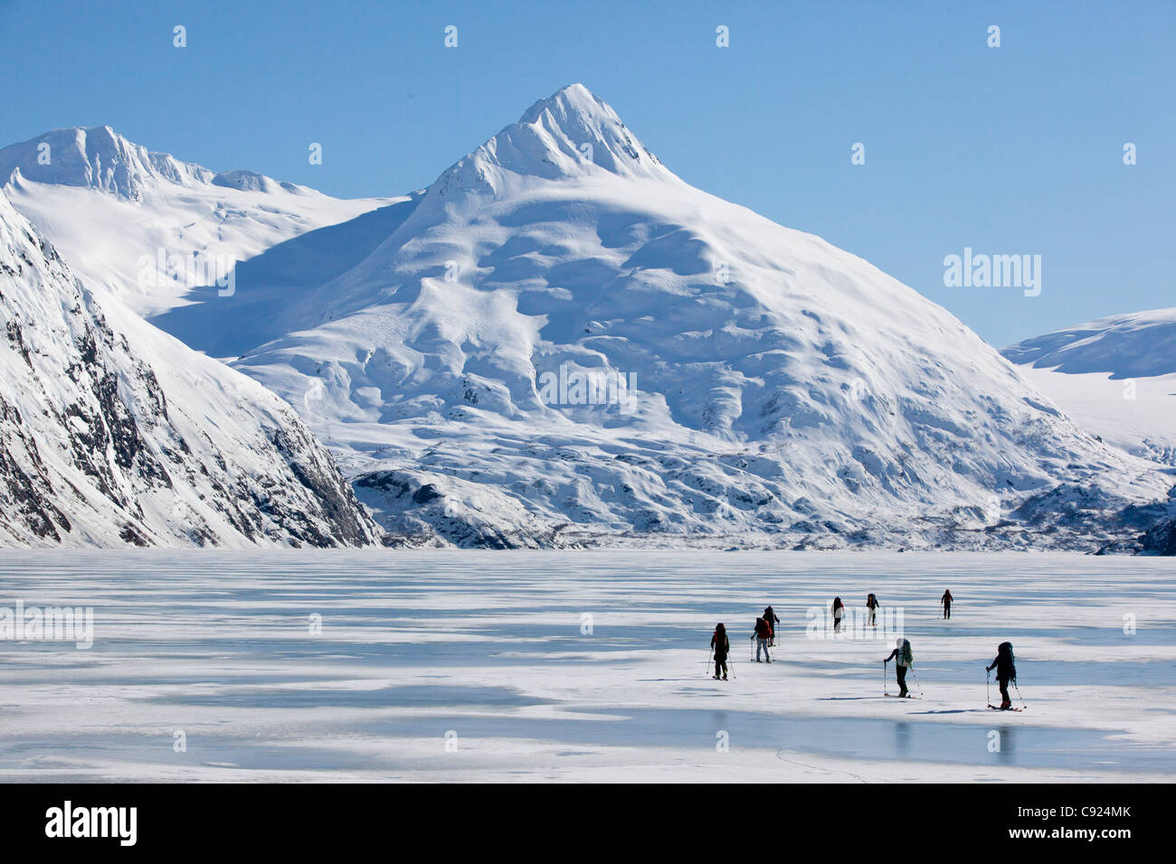 A group of skiers ski across frozen Portage Lake with Mount Bard in the ...
